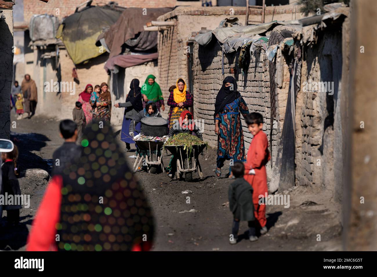 Women and children walk through a muddy alley in a poor neighborhood in ...