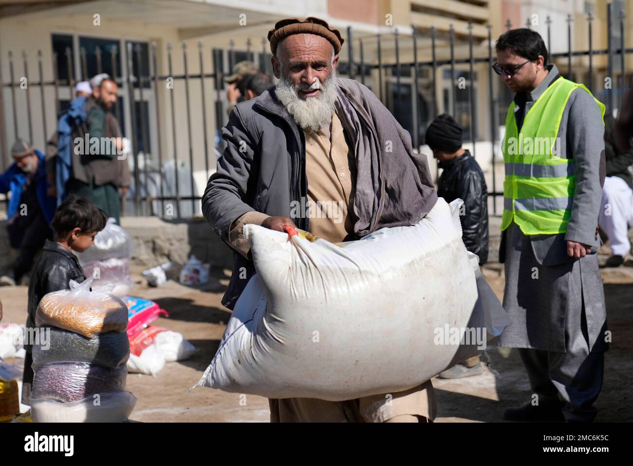 An Afghan man carries a sack of flour during a humanitarian aid ...