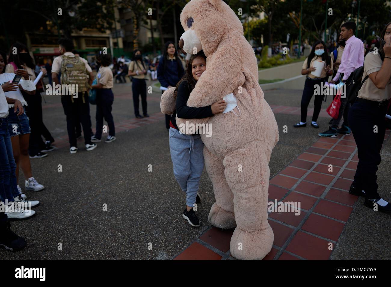 A person dressed as a teddy bear gives bear hugs to people for ...
