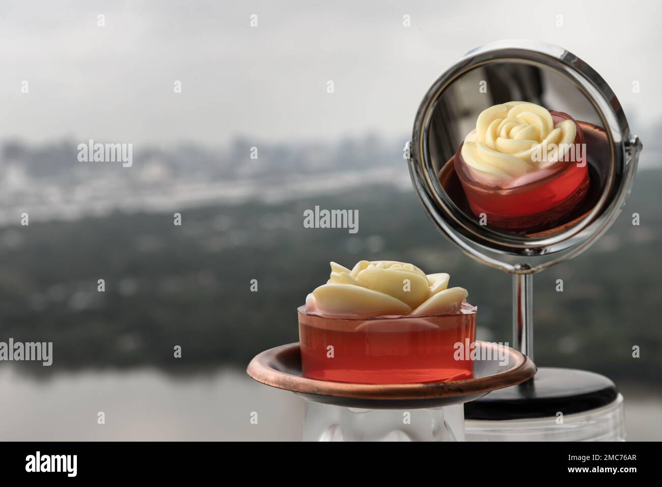 Sweet red jelly dessert layered with rose petal-shaped topping design ...