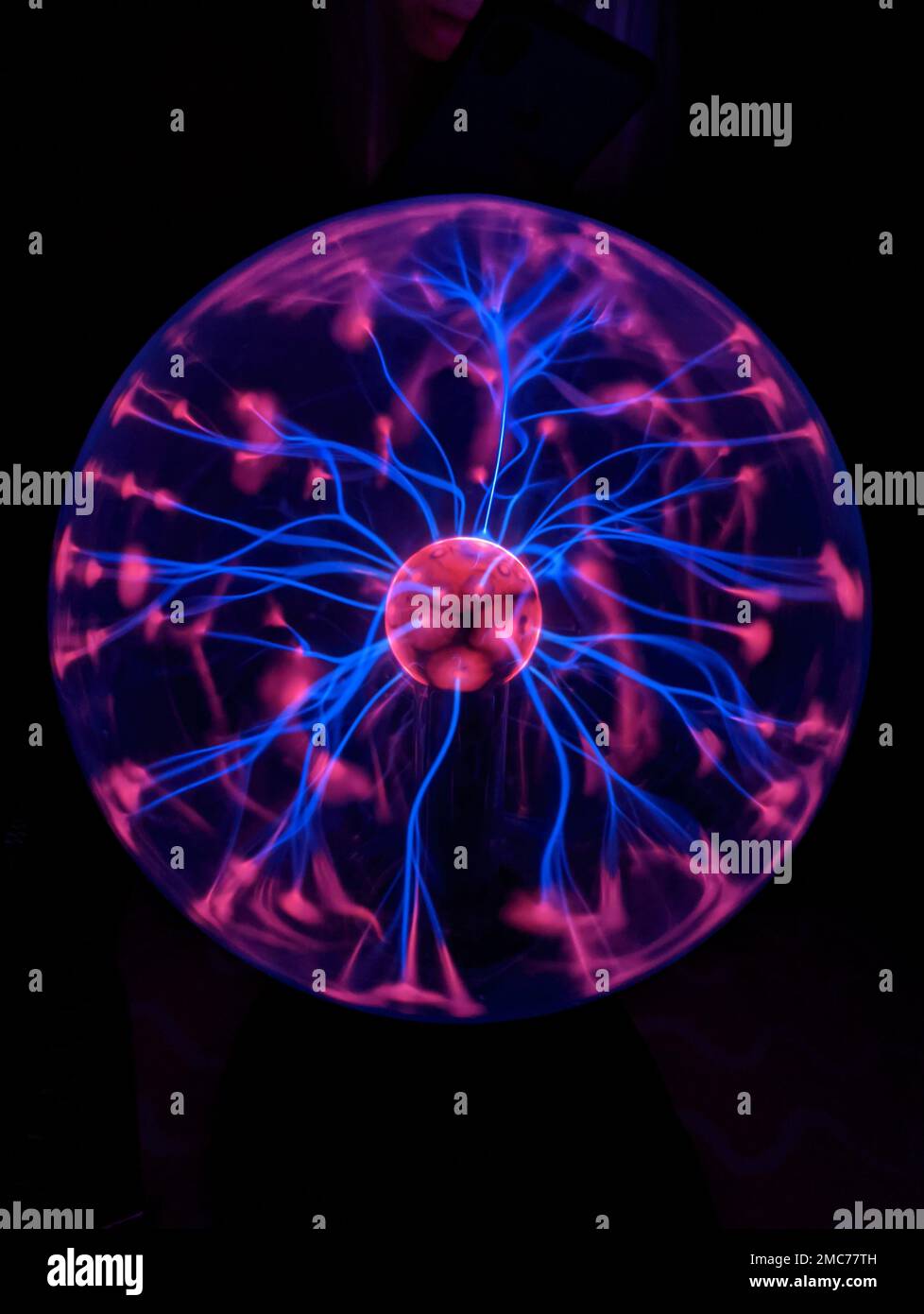 A vertical shot of a plasma lamp isolated on the dark black background ...