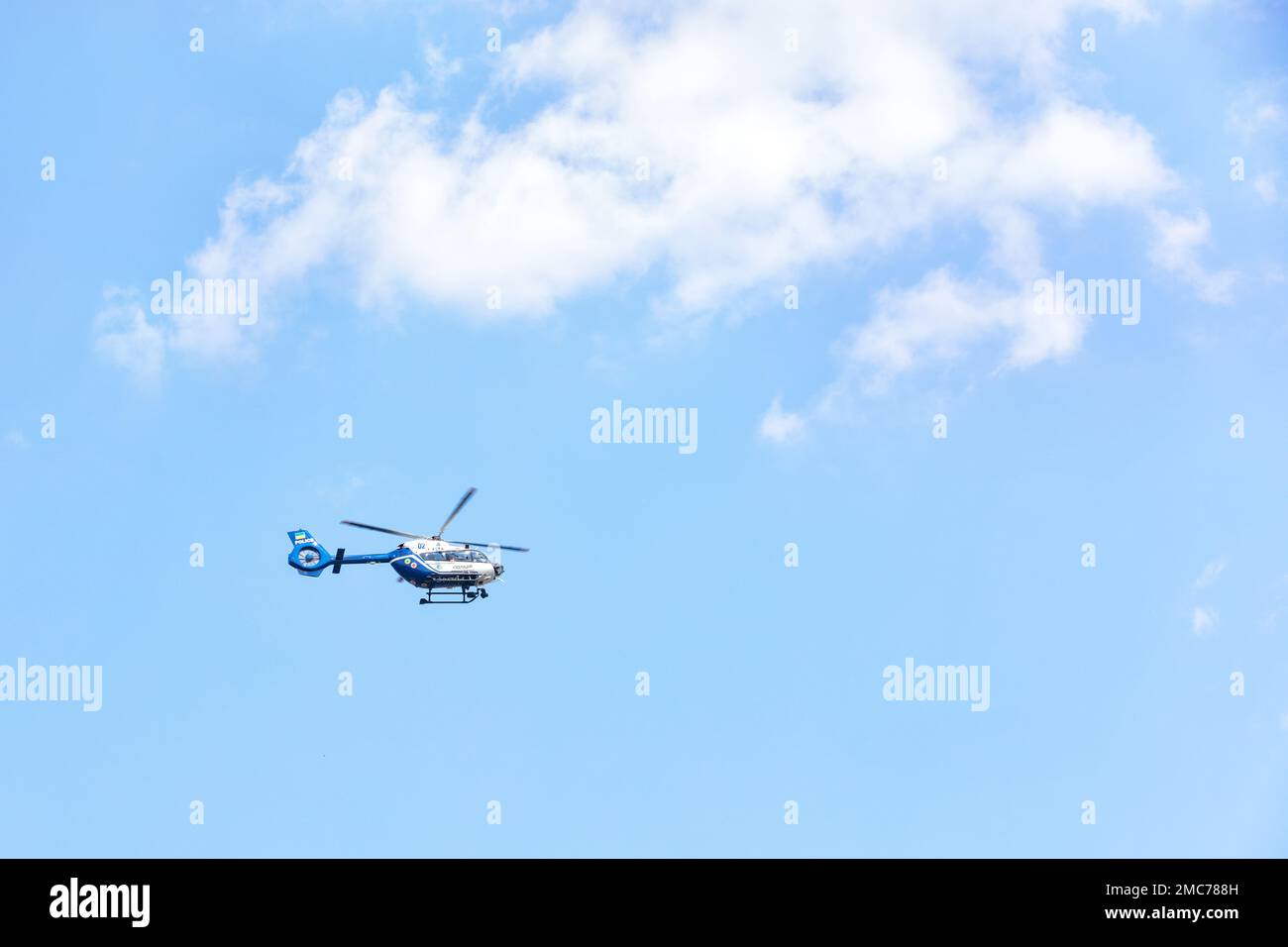 A helicopter of the National Police of Ukraine flies in profile against ...