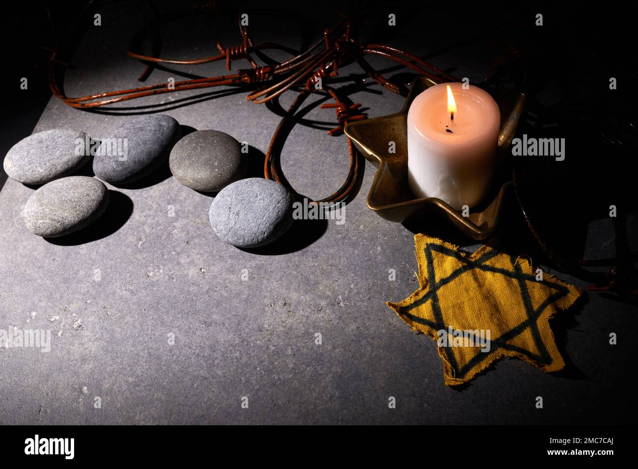 Holocaust memory day. Barbed wire, stones, yellow star and burning ...
