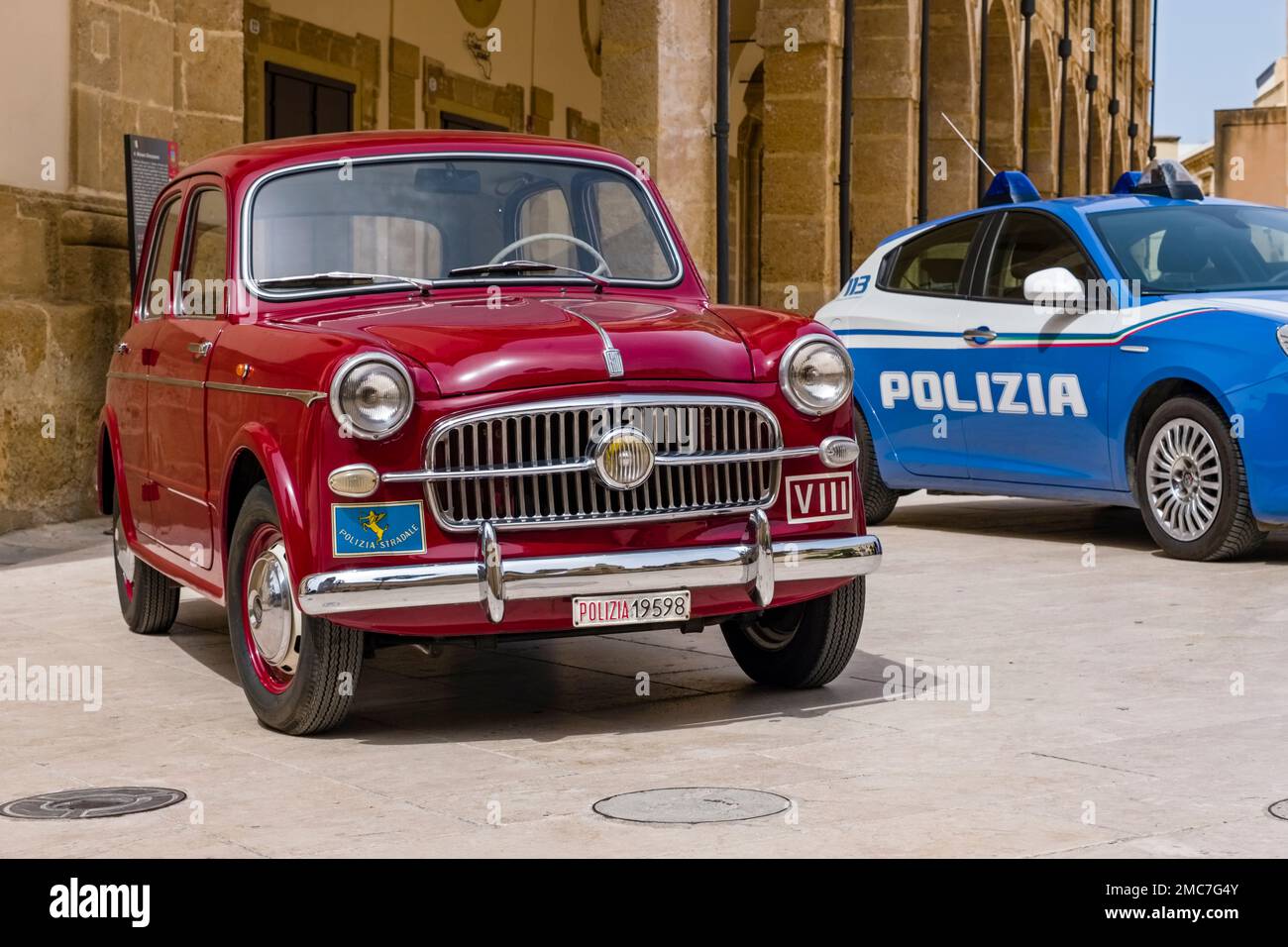 A red Fiat 1100 Polizia Stradale is parked in front of a new blue ...