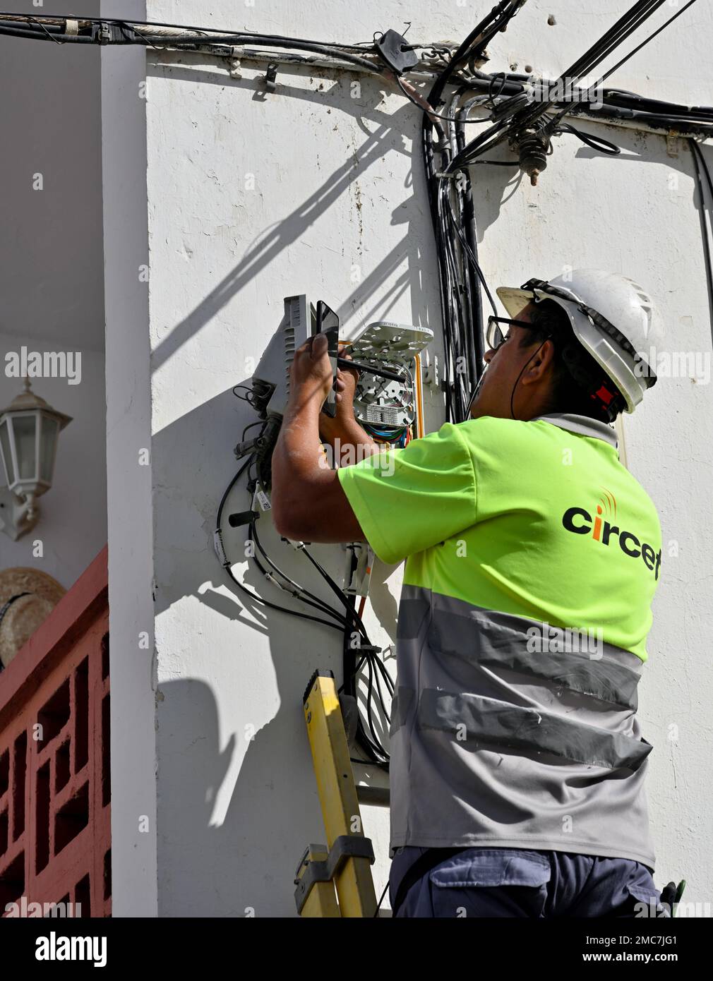 Engineer working at top of ladder installing fibre optic cable Stock ...