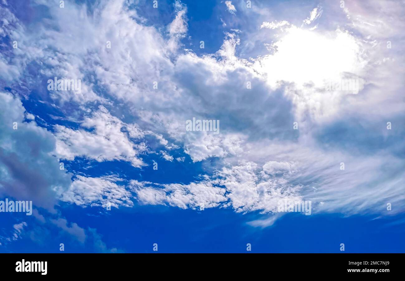 The sun comes out from behind the clouds with blue sky background in ...