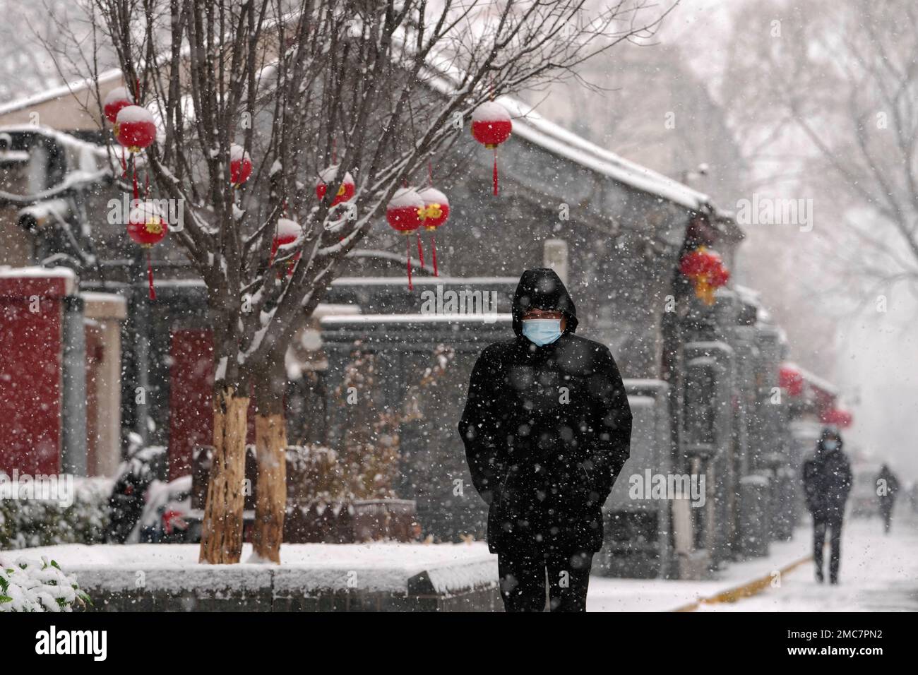Residents walk along a hutong alley decorated with the red lanterns ...