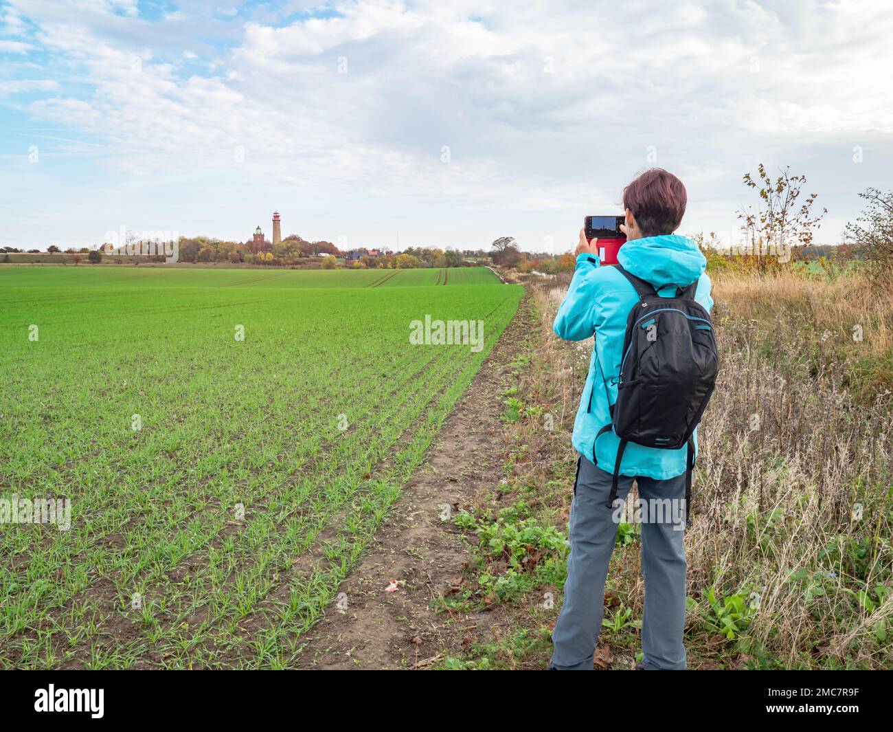 Woman takes photo of field with Cape Arkona lighthouse. Baltic Sea on ...