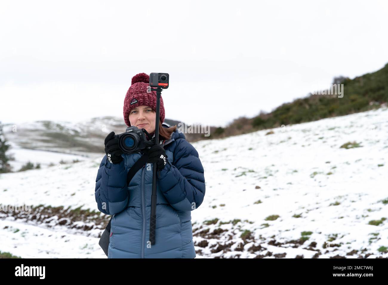 A young woman with an action camera and dslr or mirrorless camera in ...