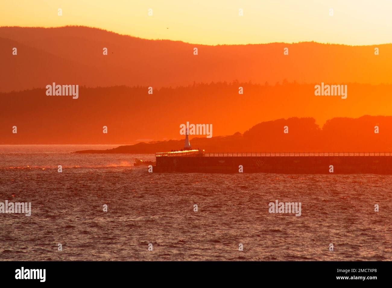 A beautiful view of an orange color sunset over the lighthouse at the ...