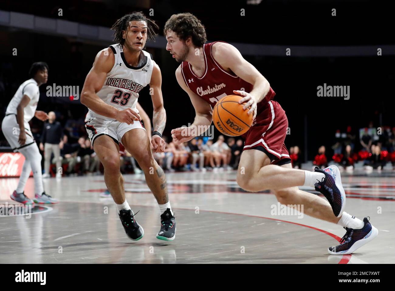 Charleston's Ben Burnham (25) drives past Northeastern's Joe Pridgen ...