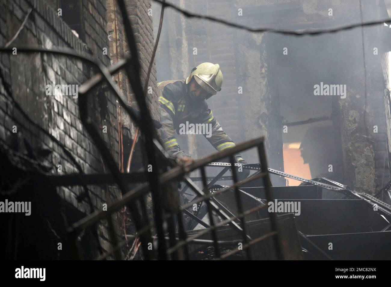 A fireman pushes out a metal shelf from a shop damaged in fire at the ...