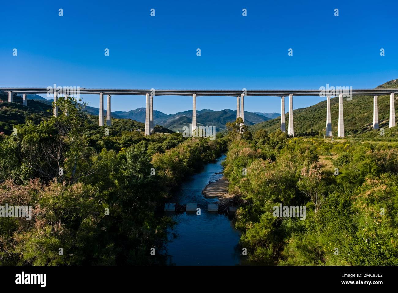 A large, long bridge of the Messina-Palermo highway spans the valley of ...
