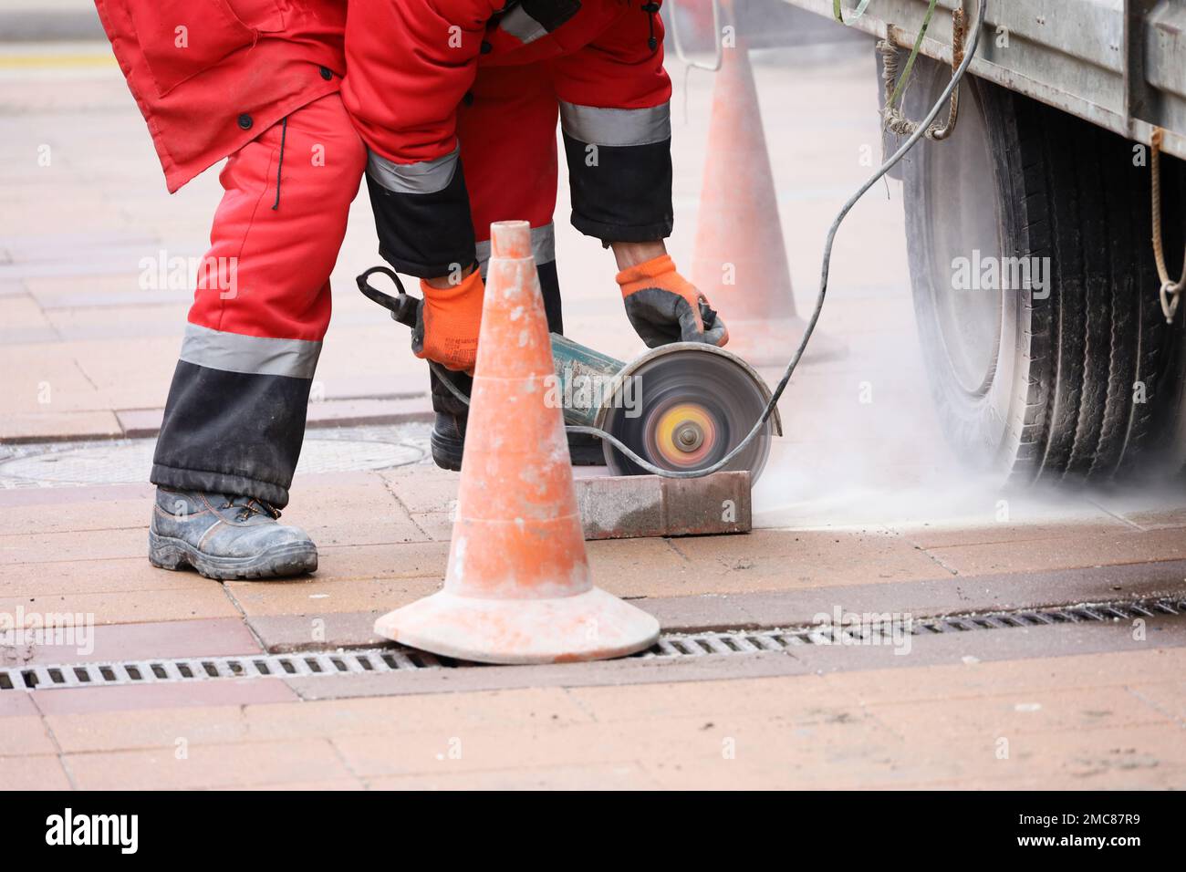 Worker saws the tile on city street, repair the road surface ...