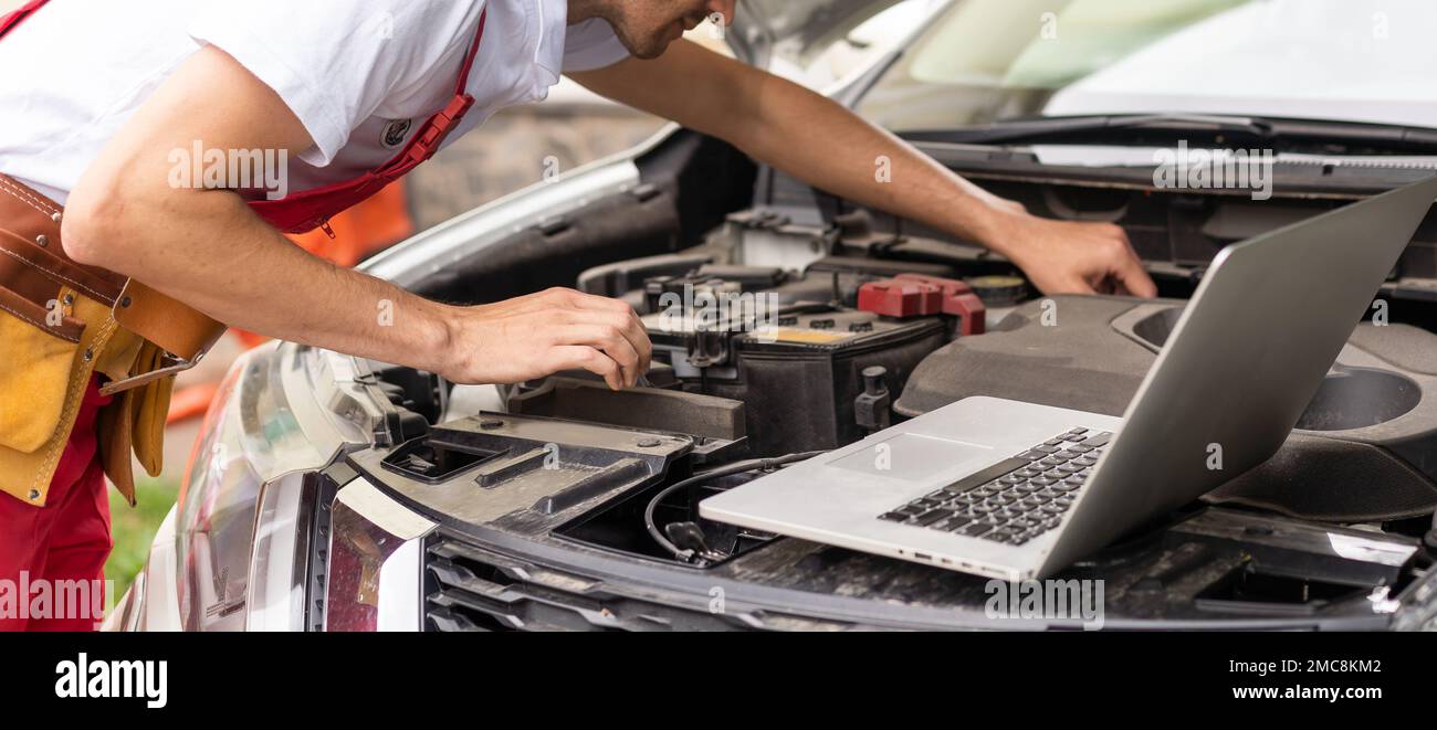 Skilled mechanic using a laptop computer to check a car engine Stock ...
