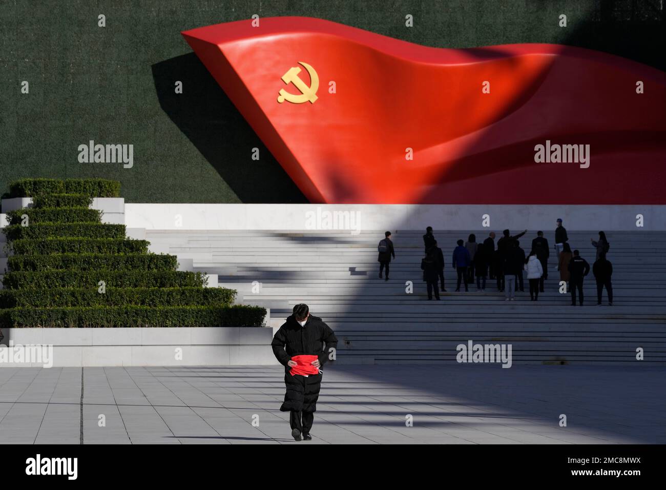 FILE - A worker folds a flag near a giant sculpture of the Chinese ...
