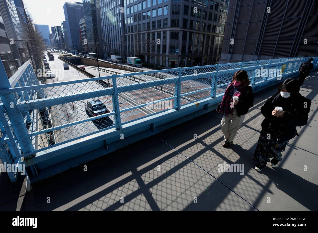 Women wearing face masks walk on a crossover bridge in Tokyo, Wednesday ...