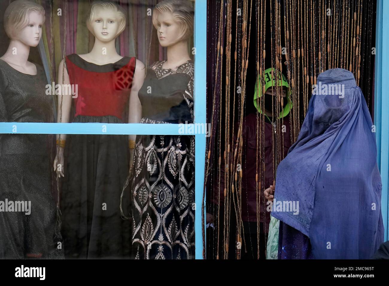 An Afghan woman wearing a burka enters a tailor's shop in Kabul ...