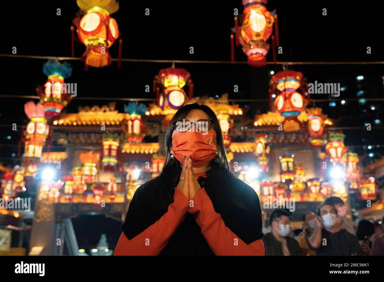 A woman wearing a face mask offers prayer at the Wong Tai Sin Temple ...