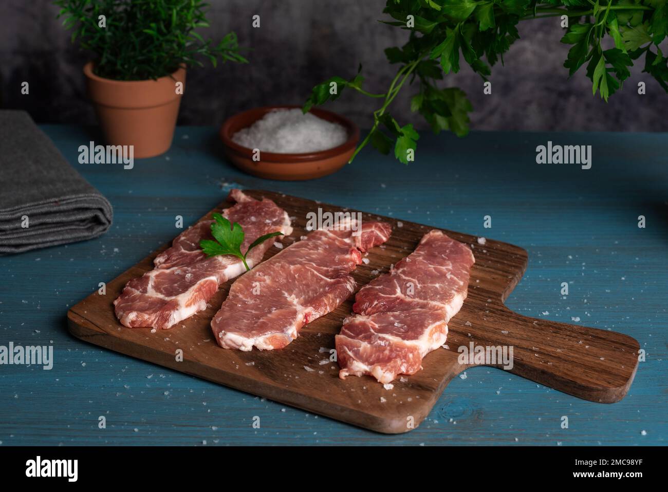 Iberian pork loin steaks on a cutting board, on a rustic wooden table ...