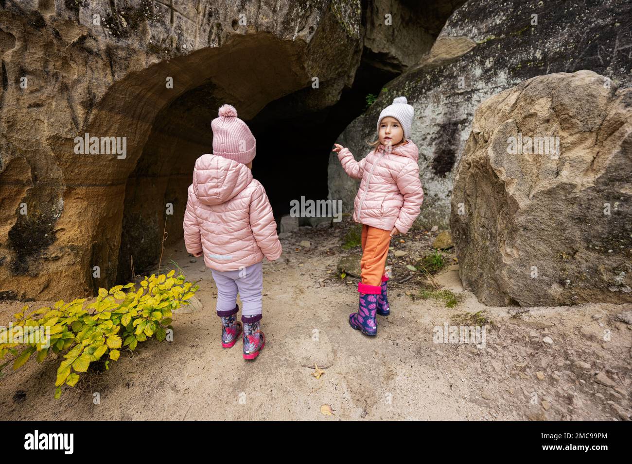 Two girls kids explore limestone stone cave at mountain in Pidkamin ...