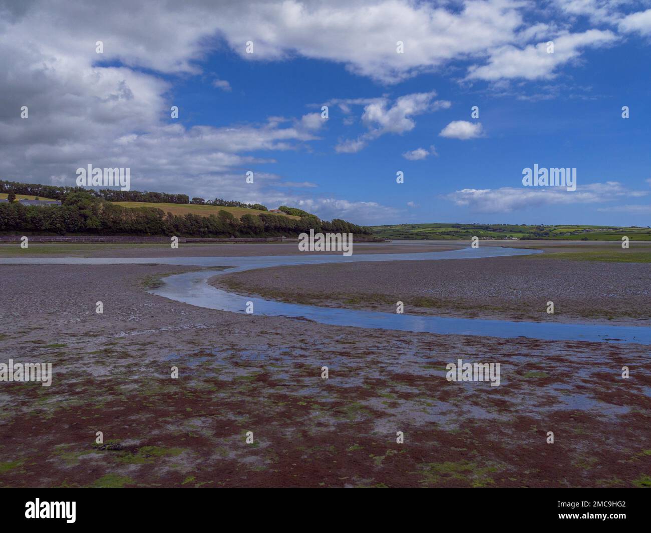 Open seabed after low tide, swampy area. Green hilly landscape on a ...