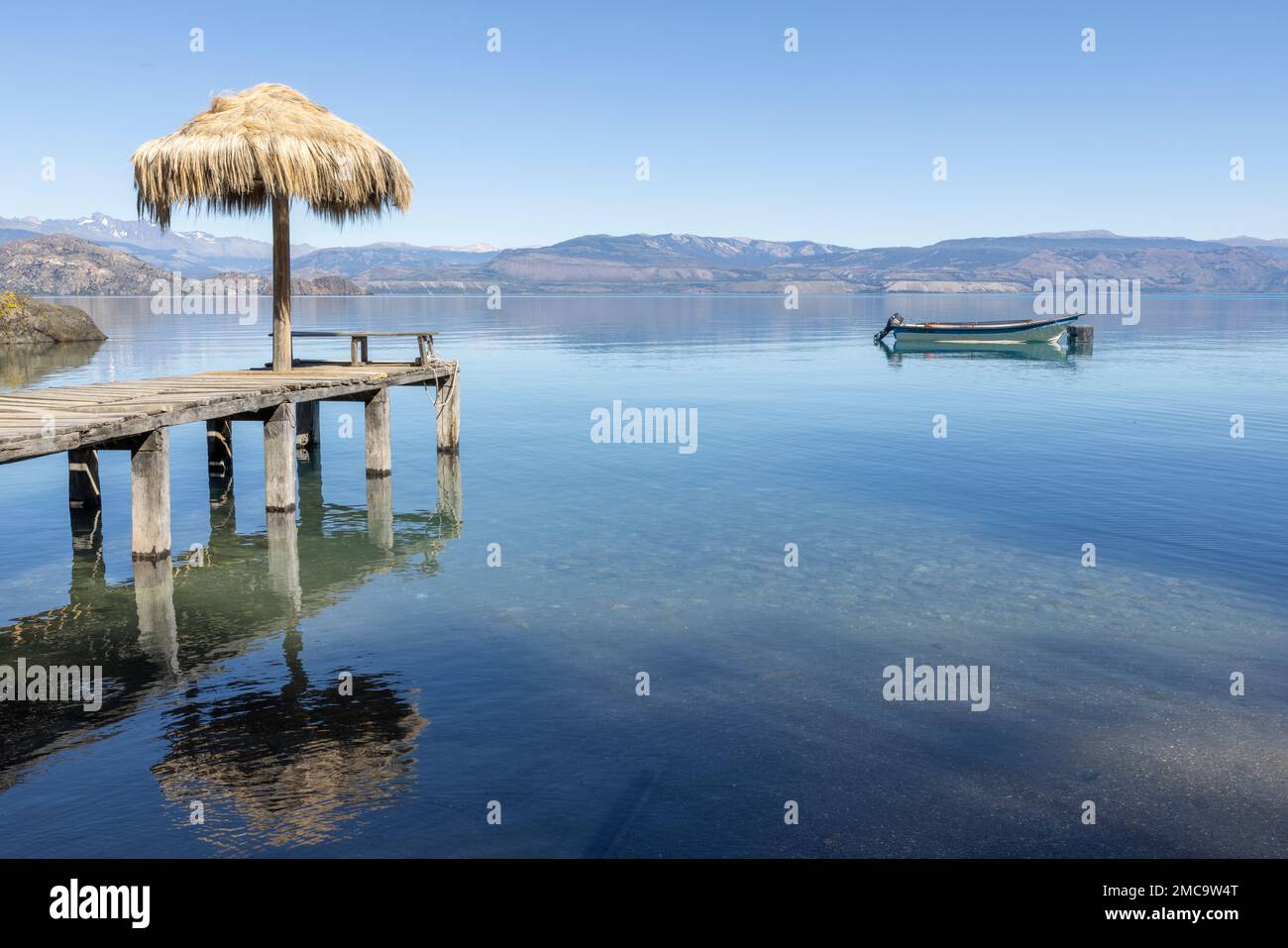 Wooden runway with a parasol made of straw and a small fishing boat on ...