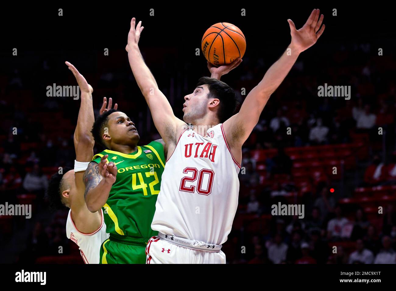 Oregon guard Jacob Young (42) shoots between Utah guard Marco Anthony ...