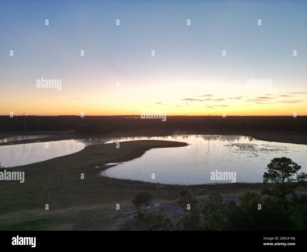 A beautiful scenery of a vibrant sunset in the sky with a lake in a ...