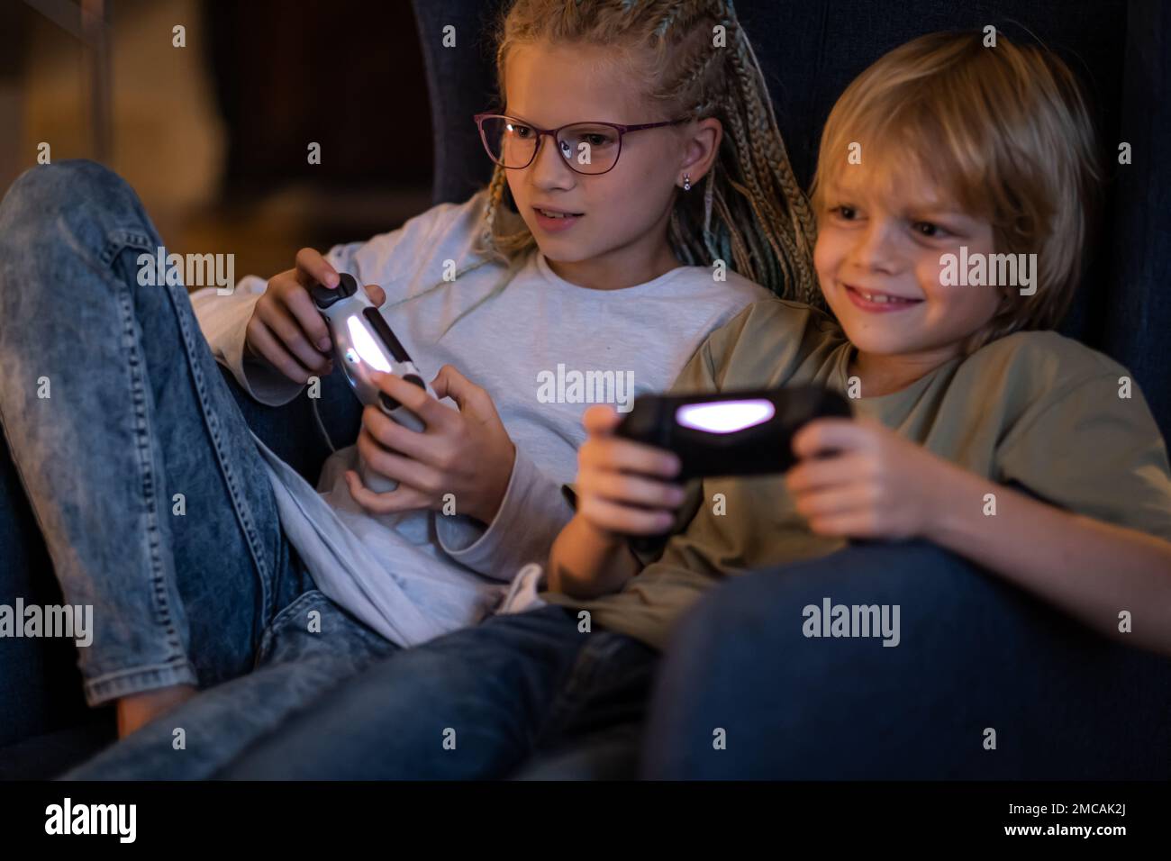 boy and girl playing video game console using joystick or controller ...