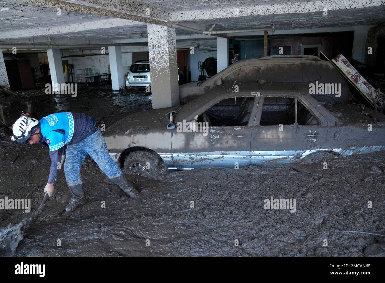 A worker shovels mud inside a parking garage, a day after a rain ...
