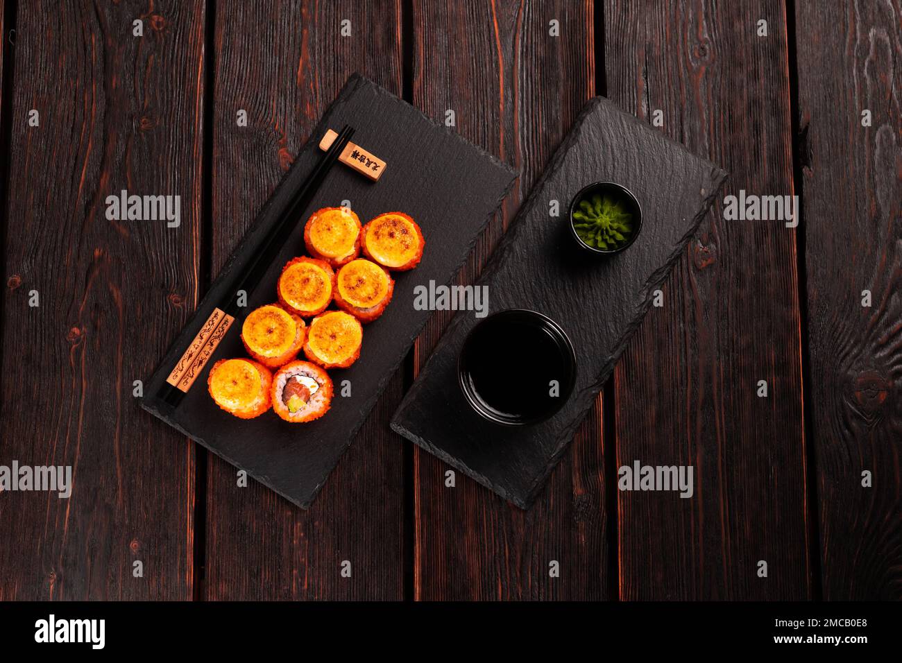 Sushi roll with salmon, avocado and tobiko caviar served on black board ...