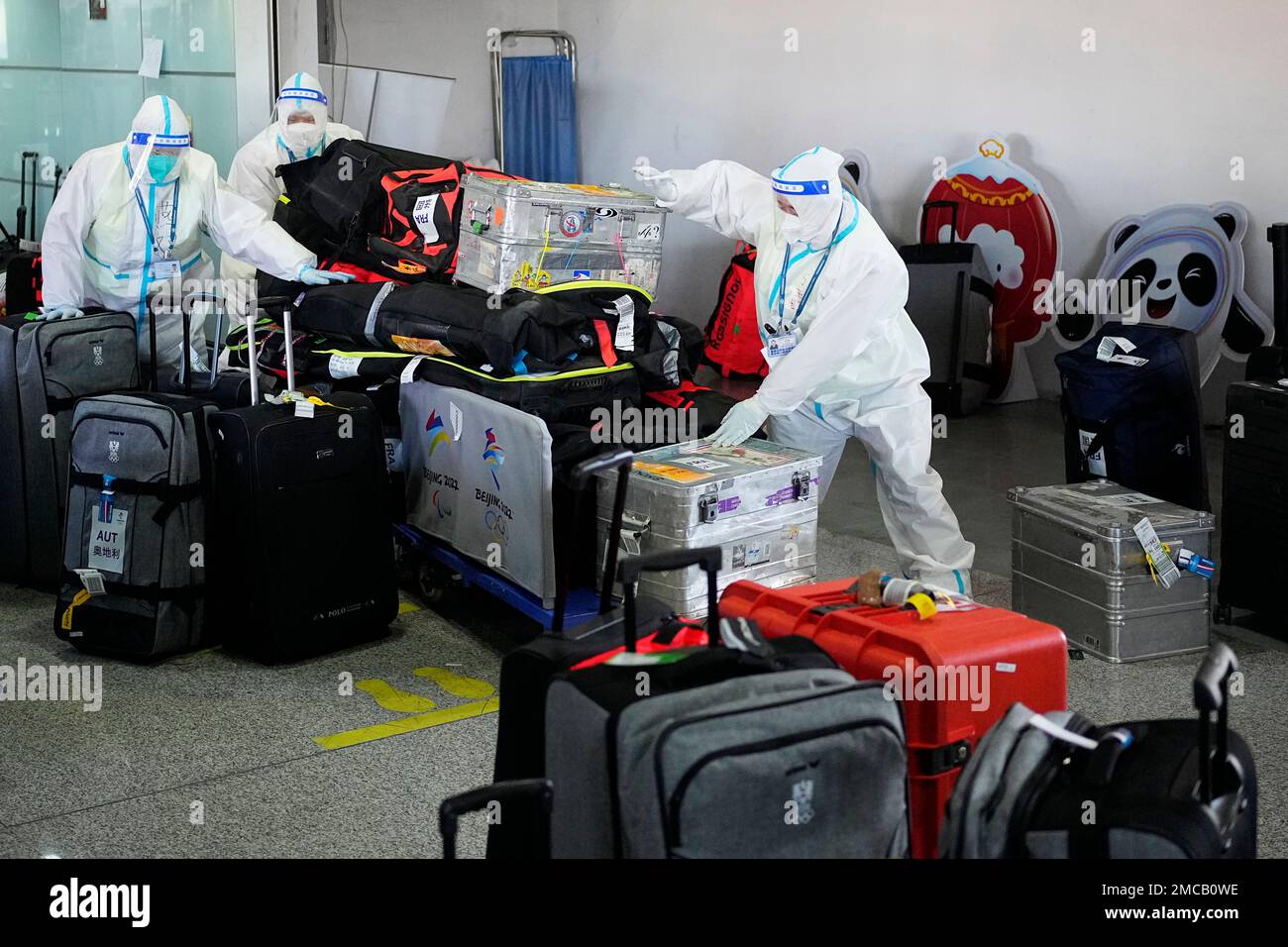 Olympic workers wearing protective gear sort luggage at the Beijing ...