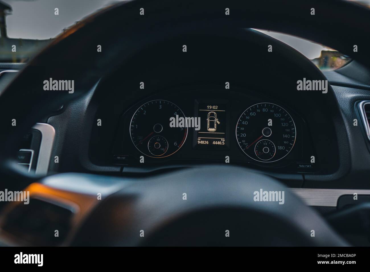 A closeup shot of a steering wheel and speed indicator in black car ...