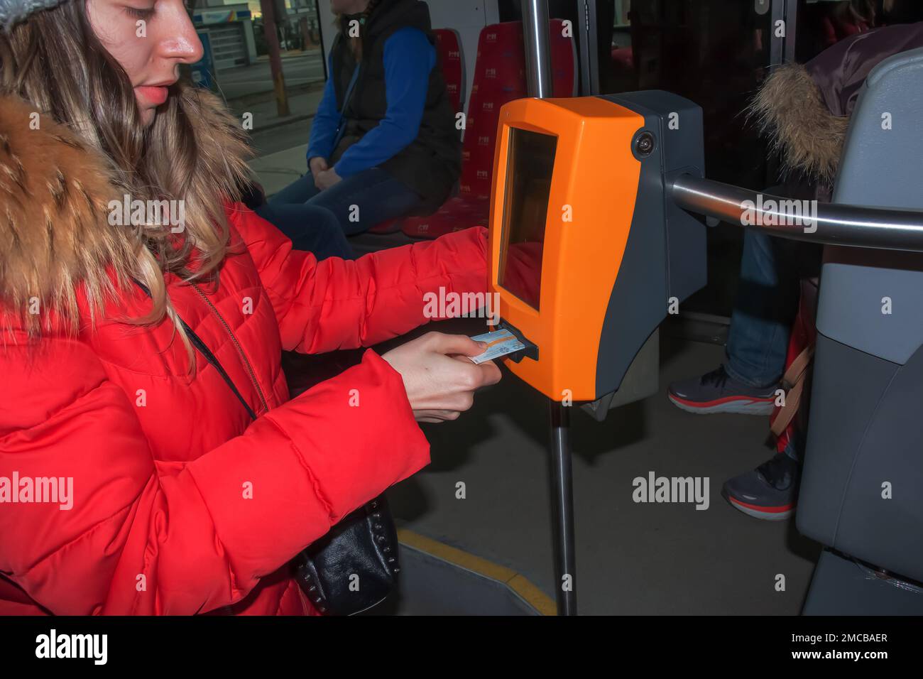 Young stylish woman using a ticket punching machine in public transport ...