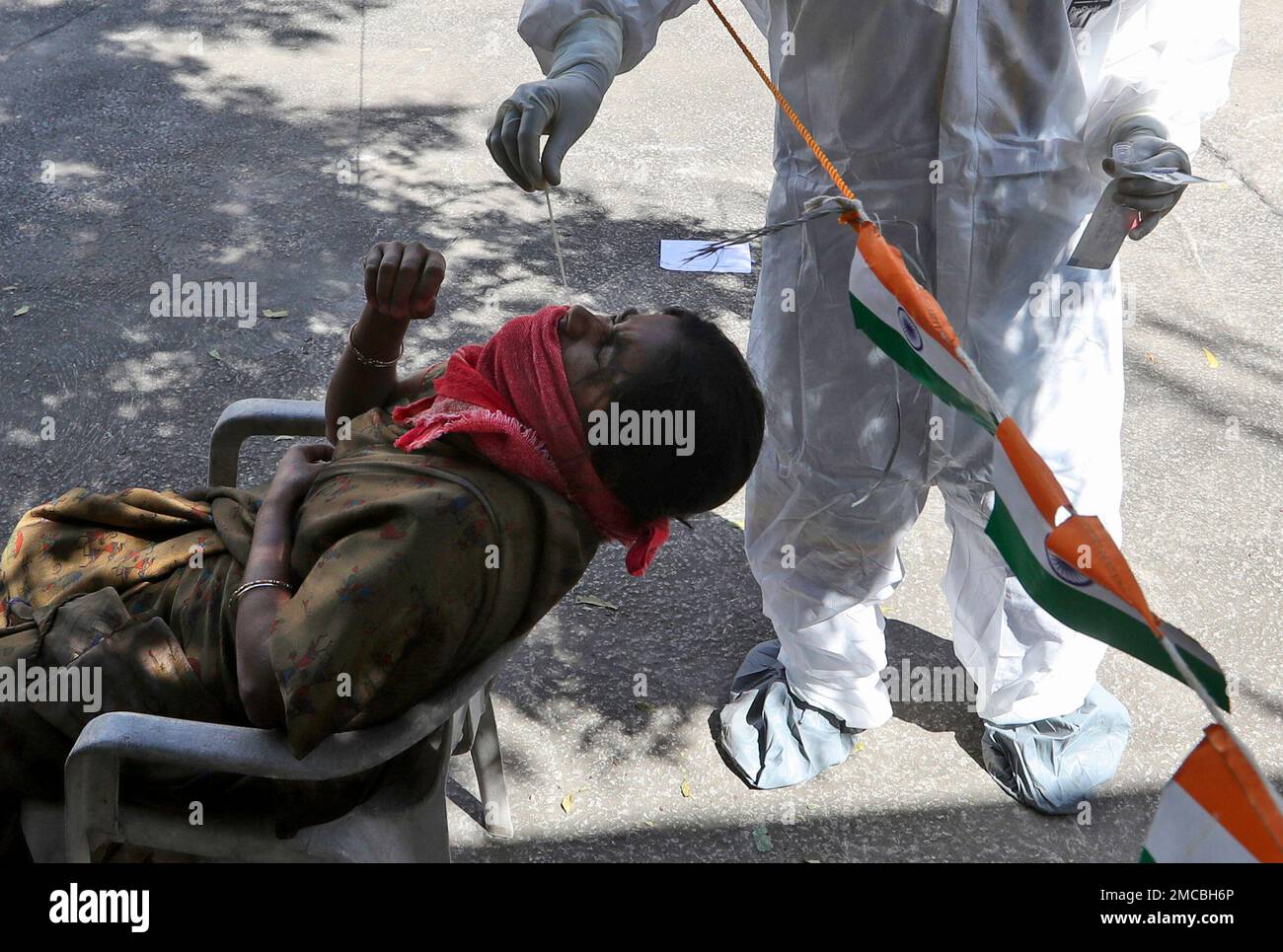 A health worker takes a swab sample of a woman to test for COVID-19 in ...