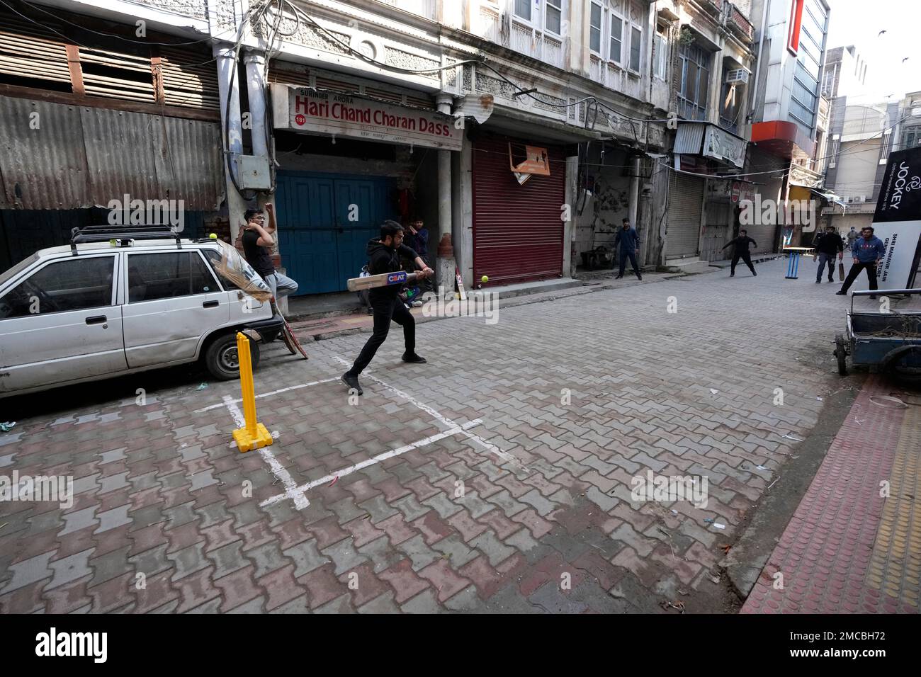 Residents play cricket in front of closed shops during a weekend ...