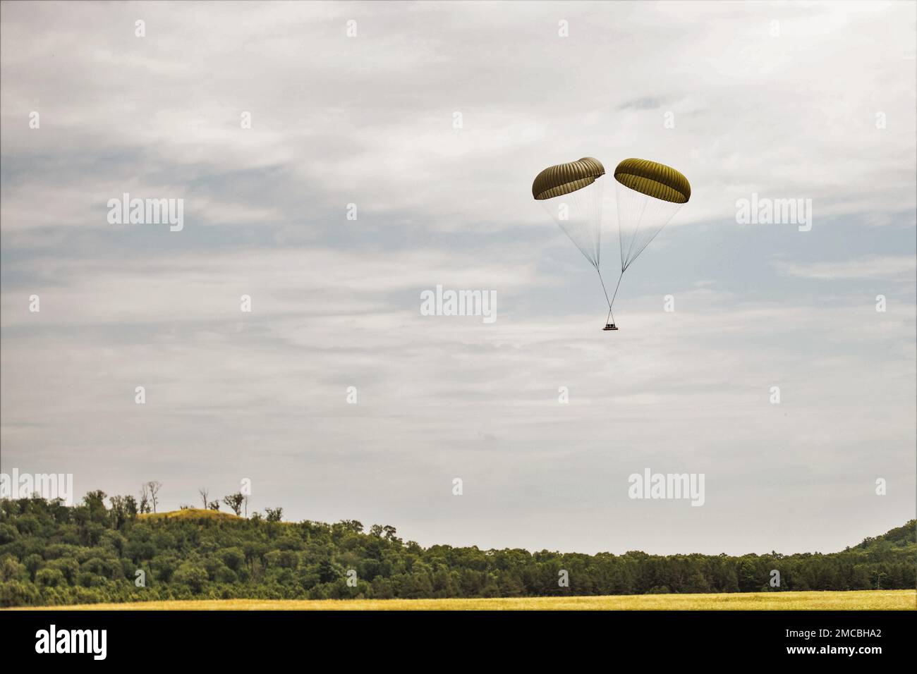 An airdrop bundle parachutes down after being released from a C-130 ...