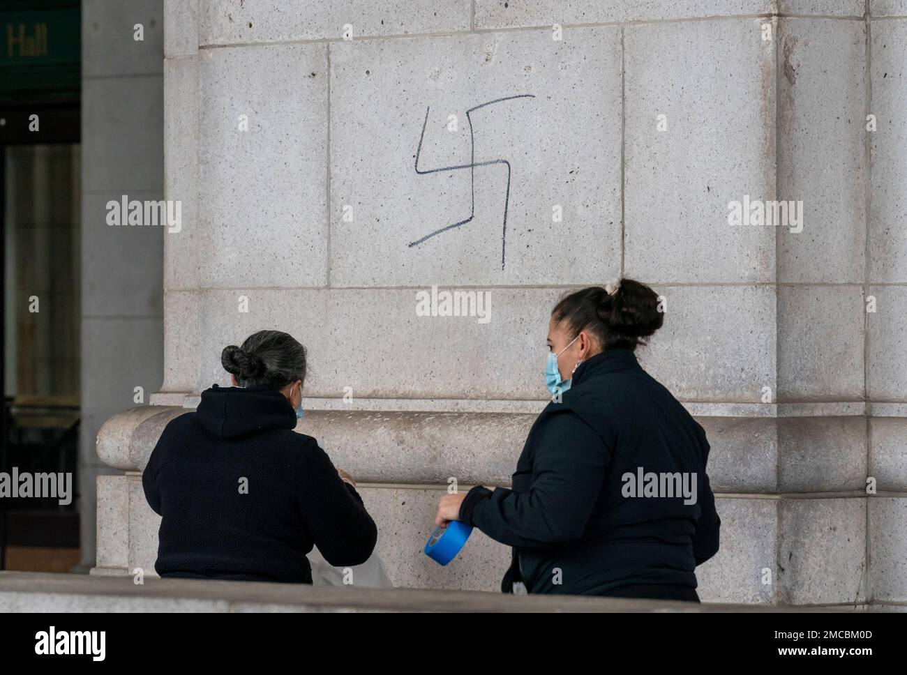 A cleaning crew prepares to cover hand-drawn swastikas on the front of ...