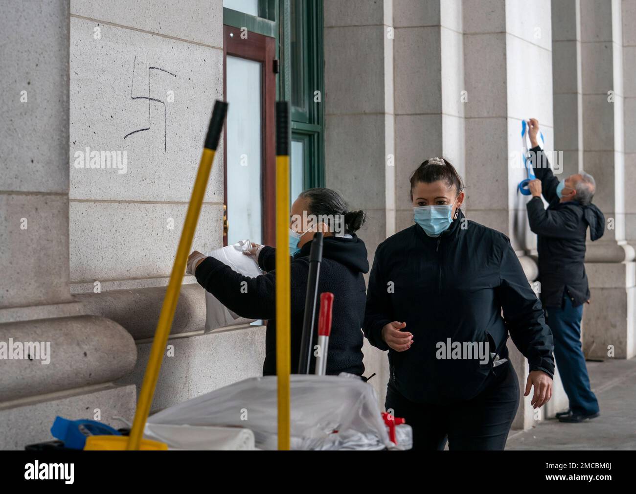 A cleaning crew covers hand-drawn swastikas on the front of Union ...