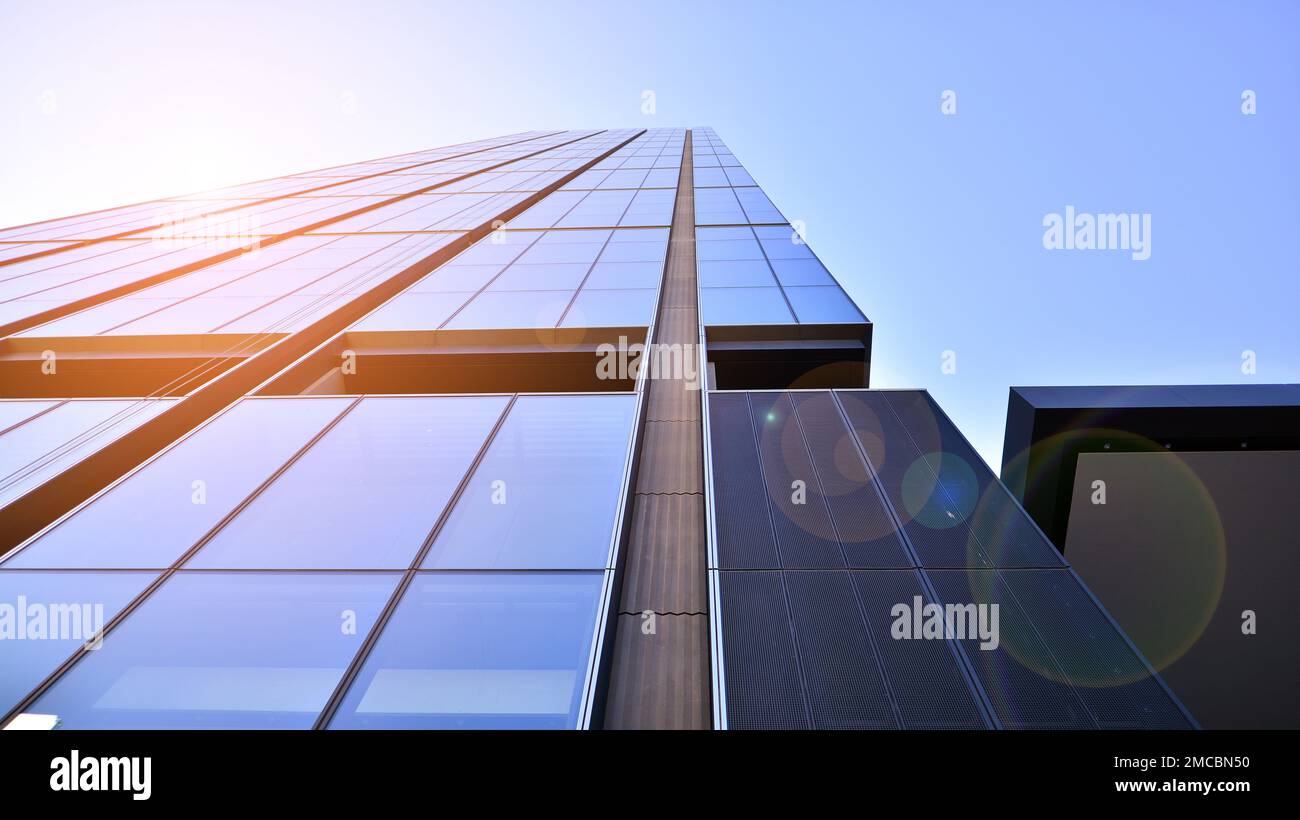 Bottom view of modern skyscraper in business district against blue sky ...