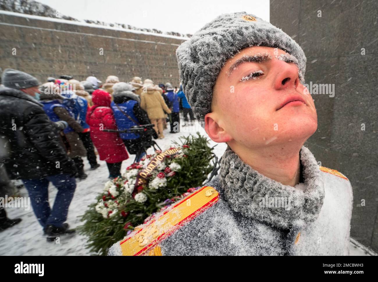 A honour guard soldier stands in snowfall as people walk to the ...