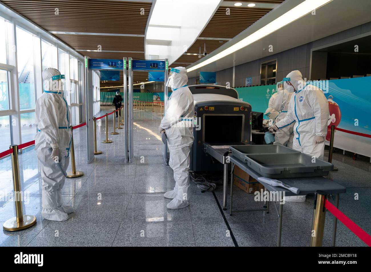 Olympic workers in protective gear work at a security check point at a ...