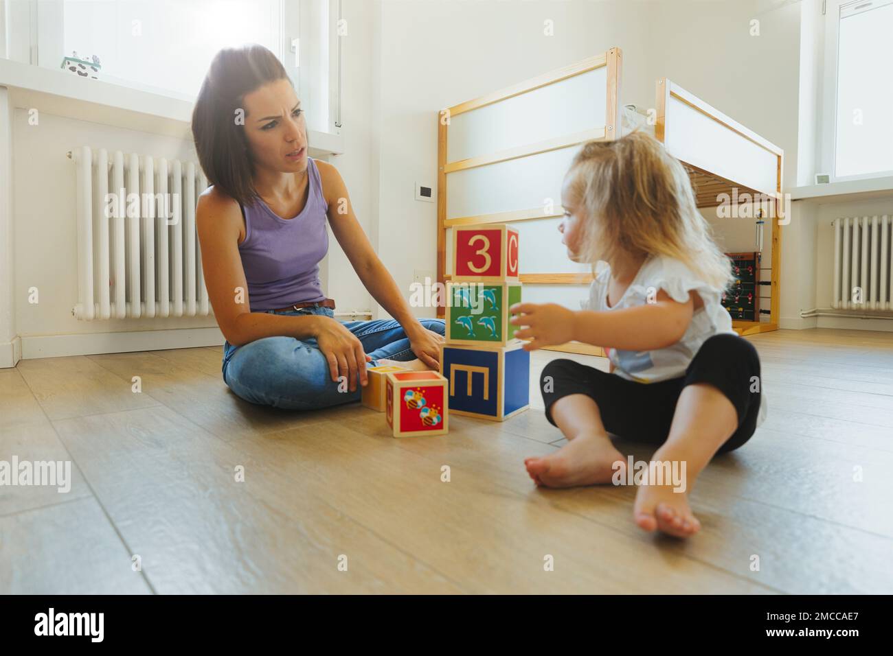 mother and daughter play with wooden cubes, with letters on the faces ...
