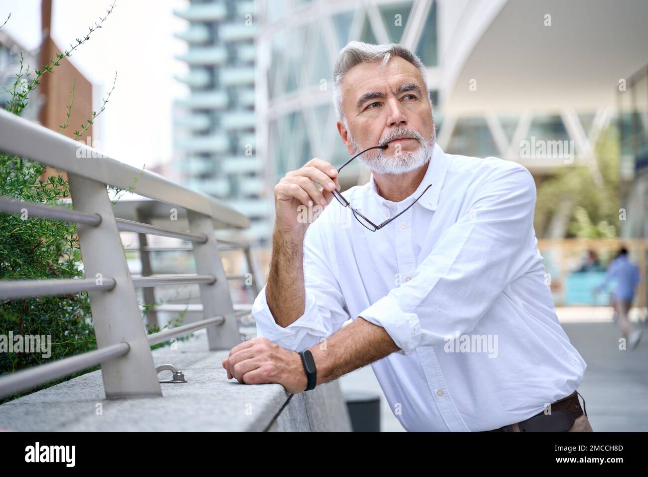 Thoughtful serious older senior business man thinking standing outdoors ...