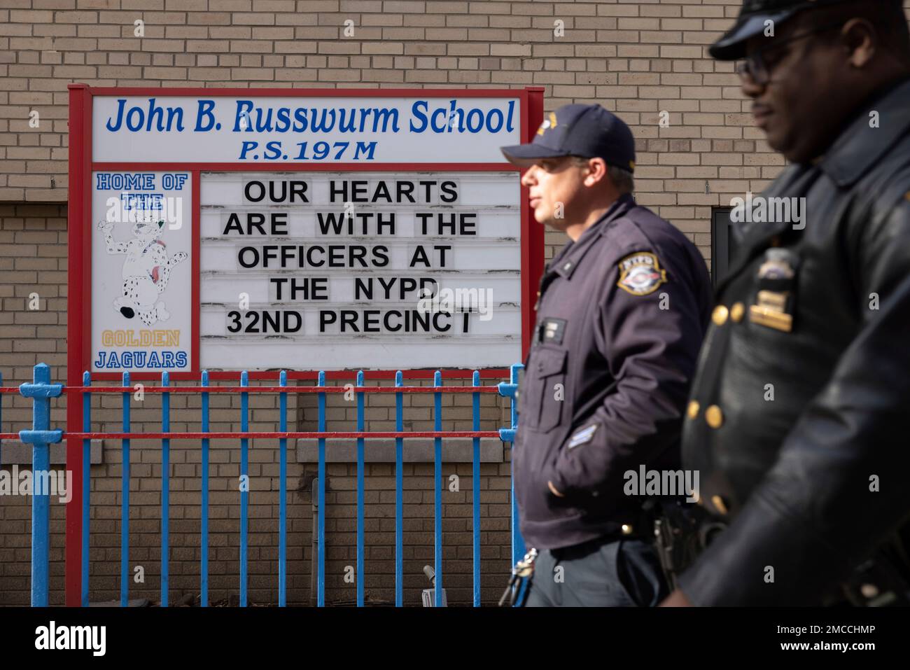 New York Police officers walk past a sign with message in support of ...