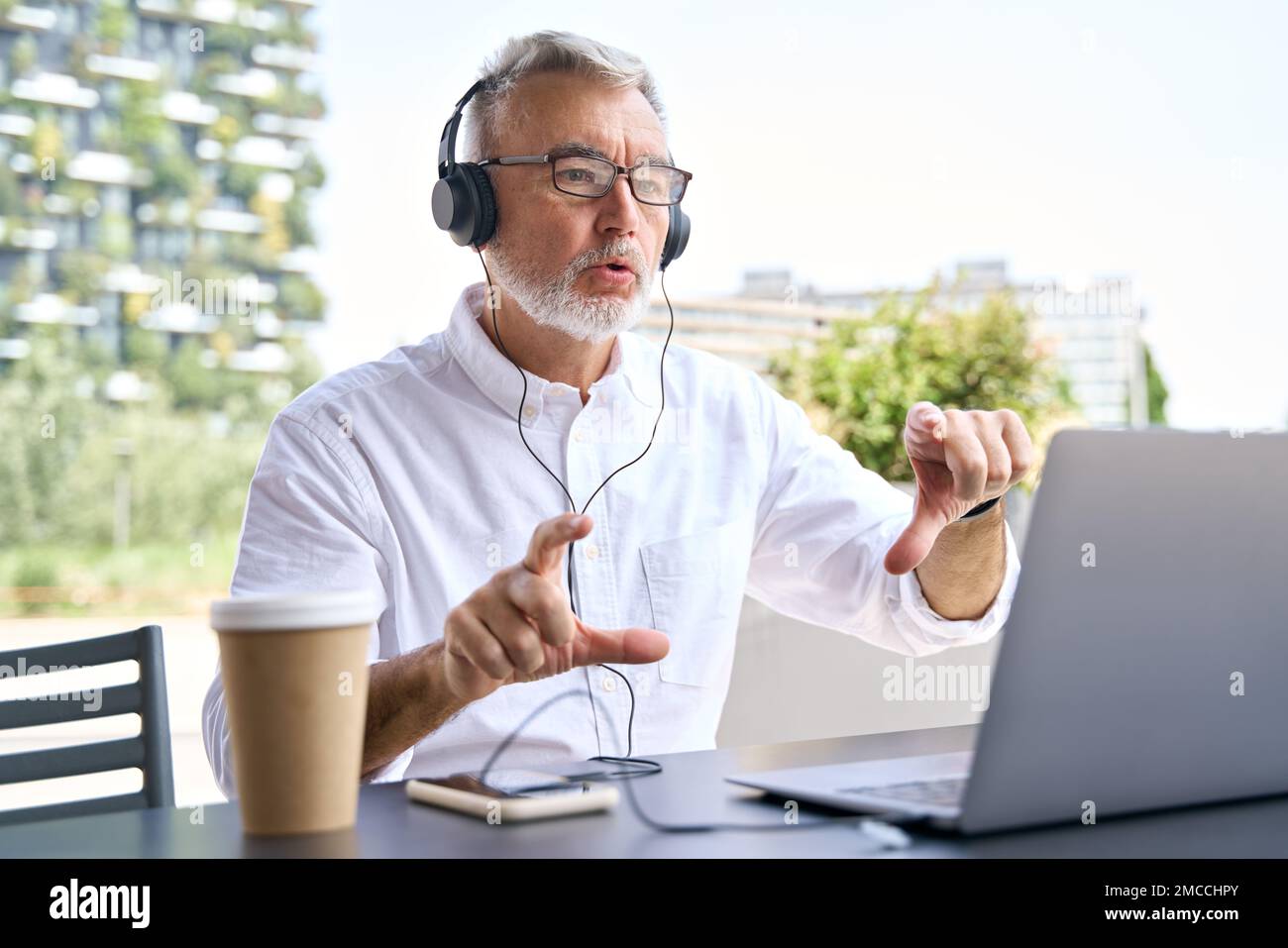 Old senior business man having hybrid remote call meeting on laptop ...