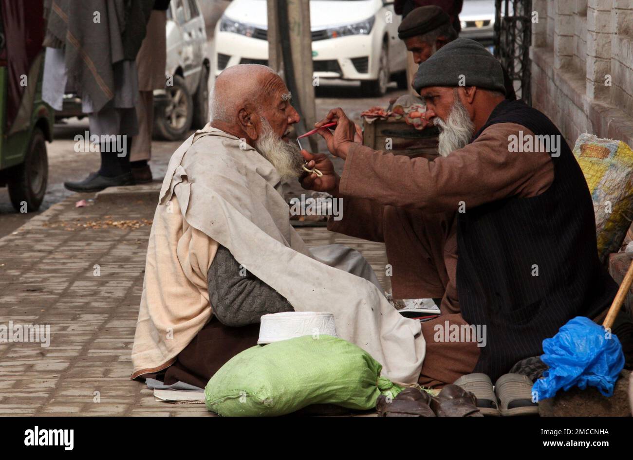 A Pakistani street barber trims a costumer's beard in Peshawar ...
