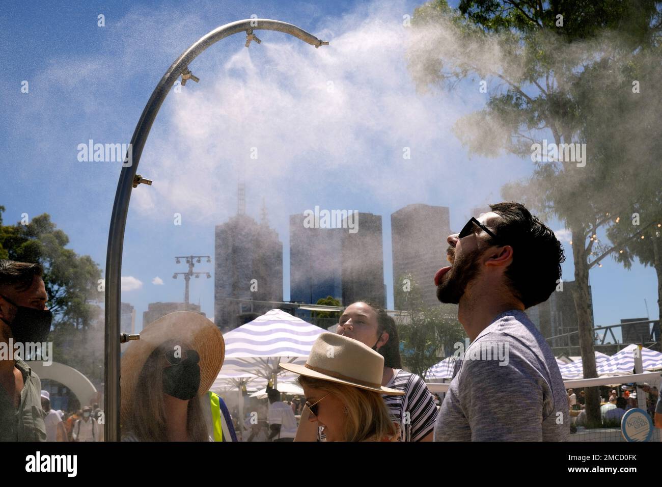 Spectators stand under cooled water misting fans at the Australian Open ...
