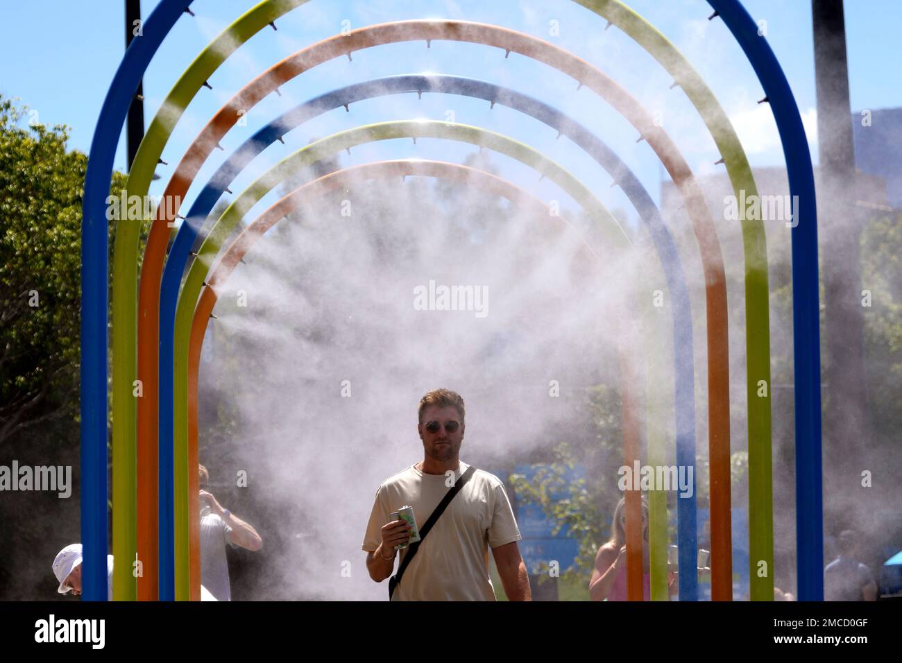 A spectators walks through a line cooled water misting fans at the ...